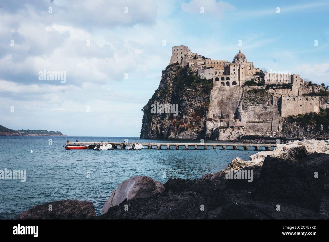 Wide shot of a wooden dock near the cliff with an old castle under the ...