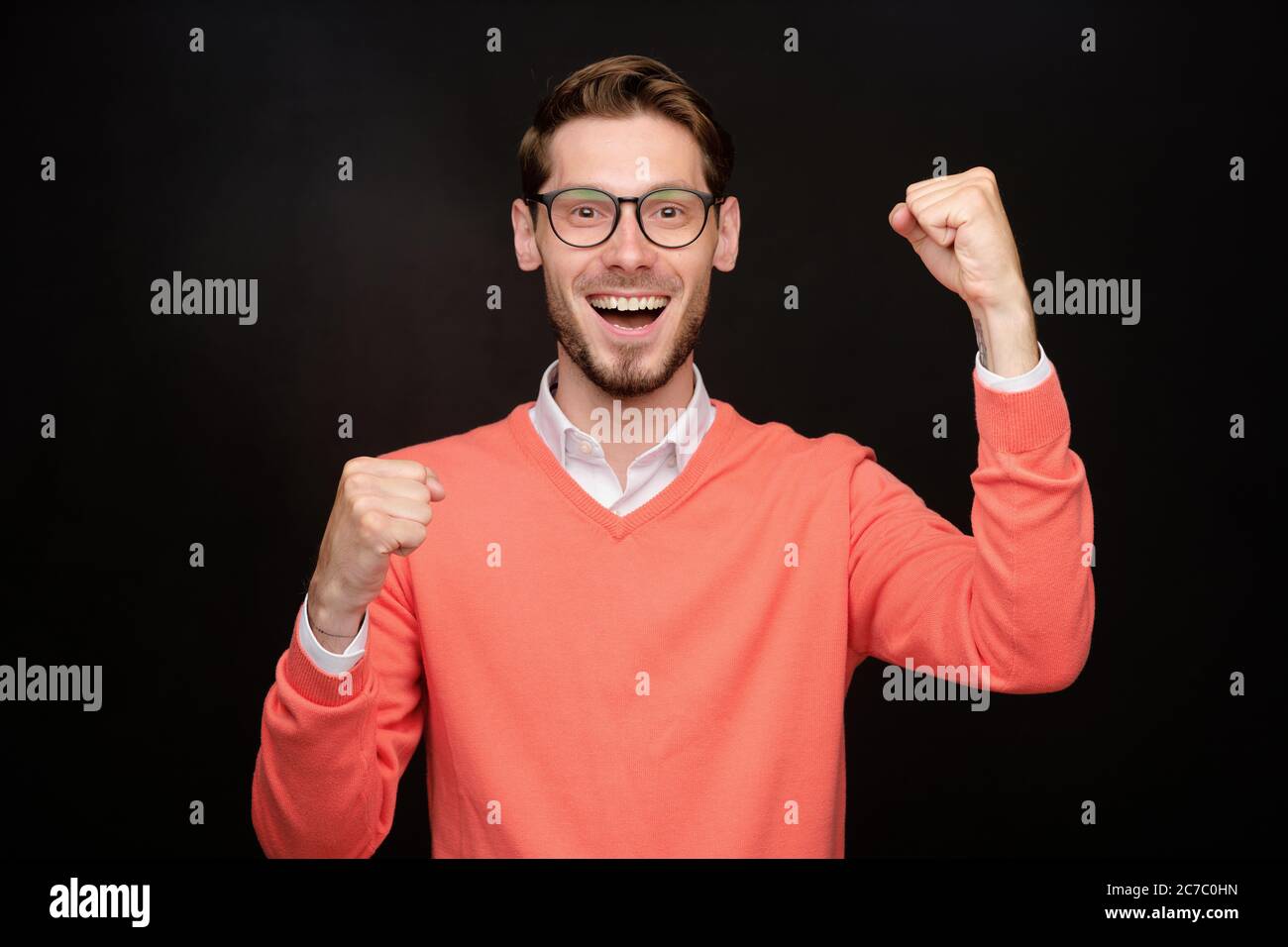 Portrait of positive excited young bearded man in glasses making yes ...