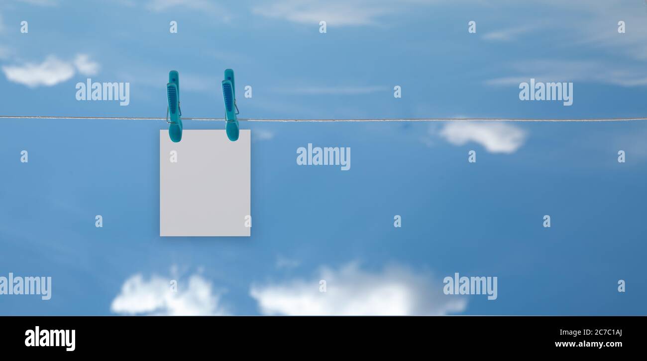 blank notes hanging on a rope with a clothespin with a bright sky ...