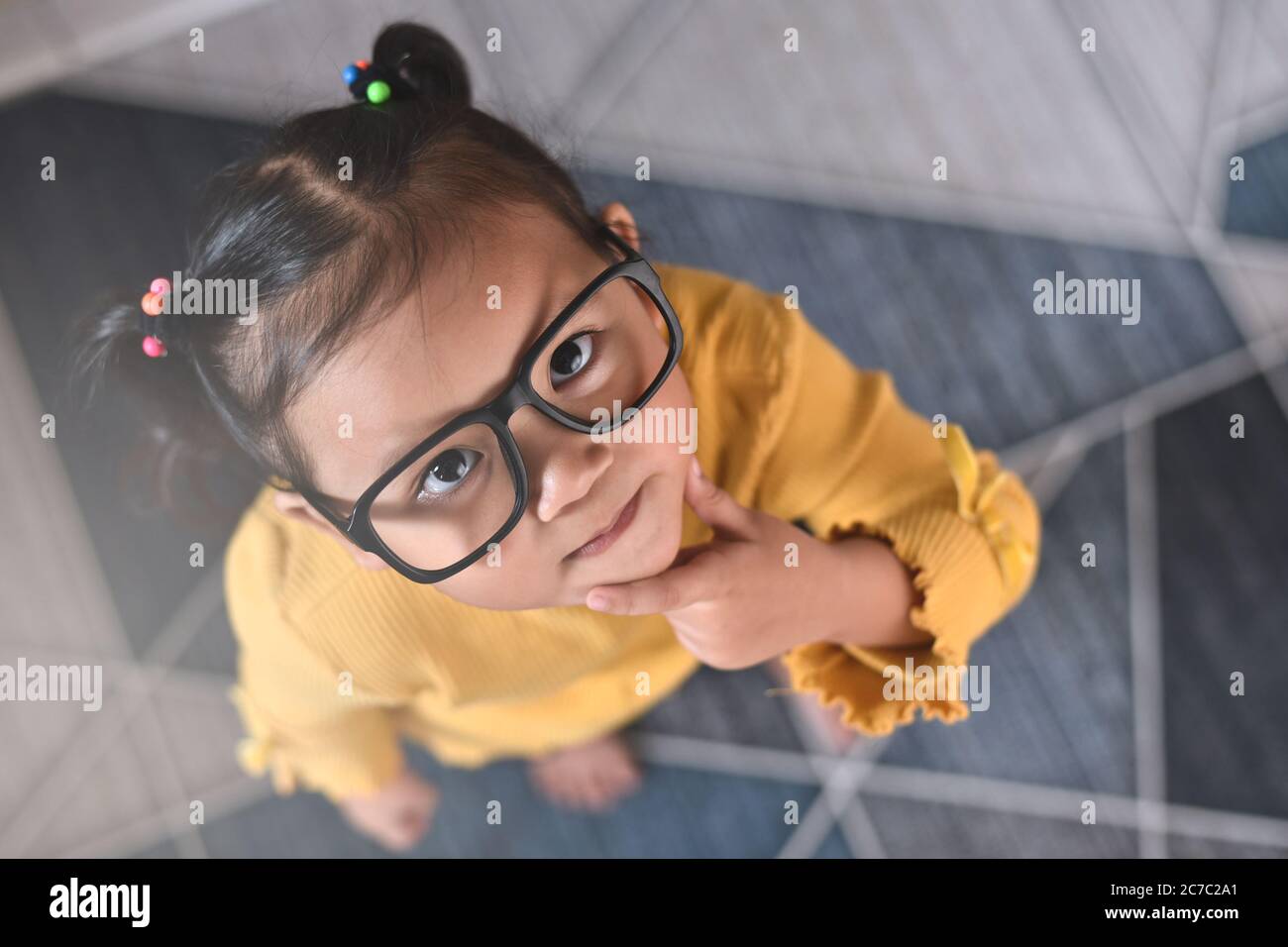 smart little asian girl with thinking gesture looking at camera ...