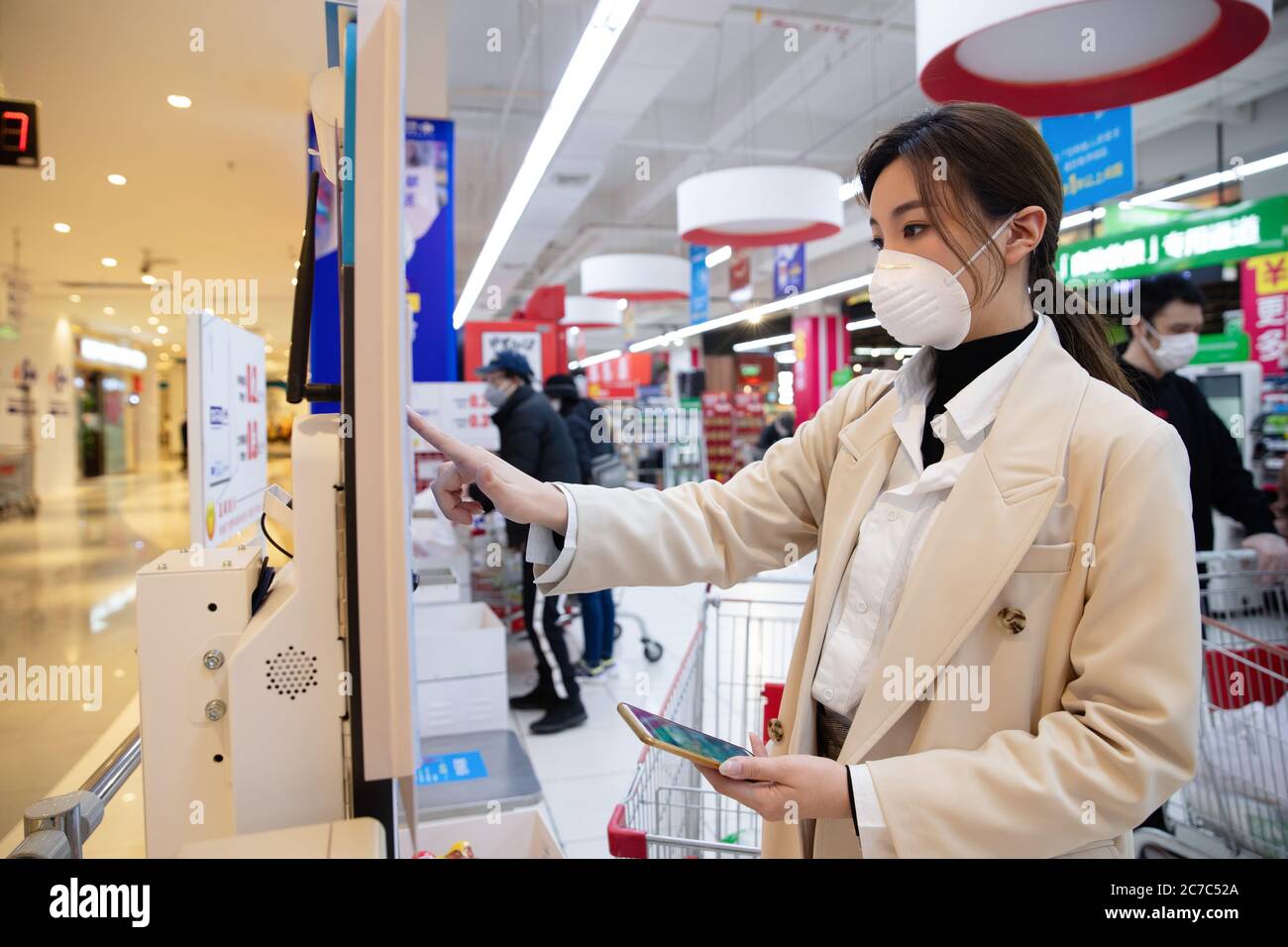 Wearing a mask of young women shopping in the supermarket Stock Photo ...