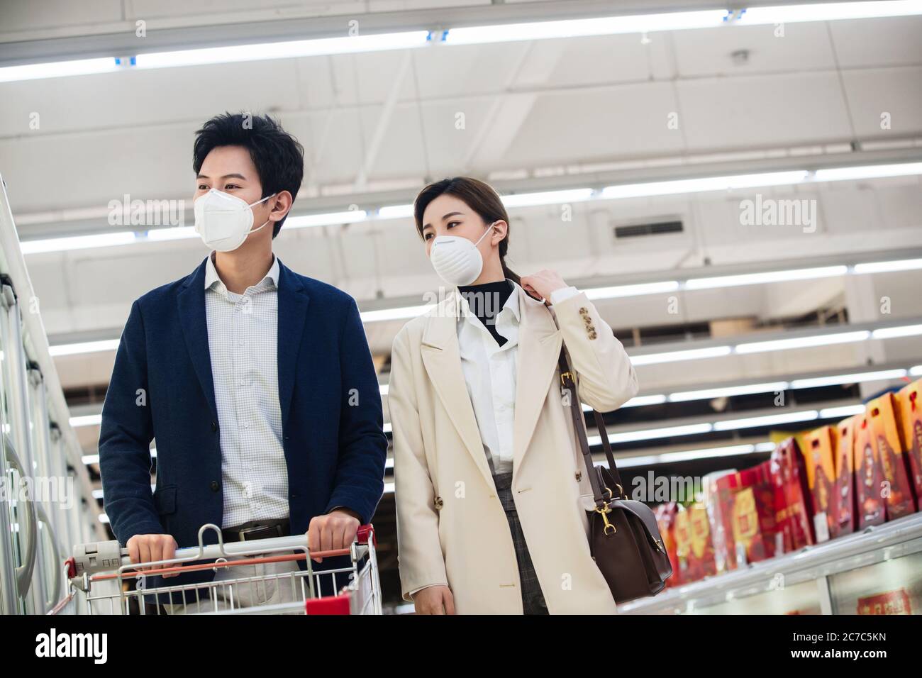 Wearing a mask of the young couple shopping in the supermarket Stock ...