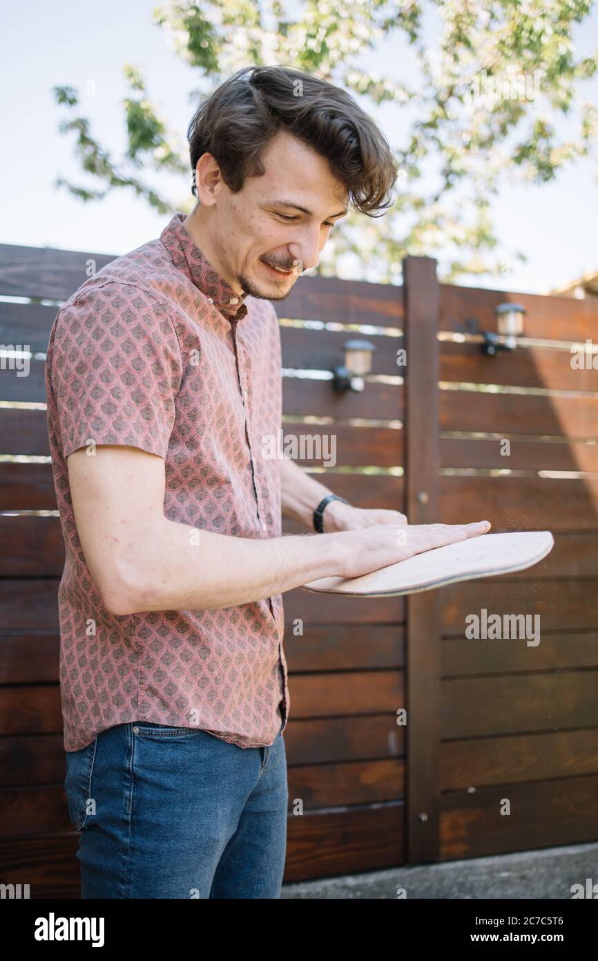 Smiling man using hand to remove wood dust from board Stock Photo - Alamy