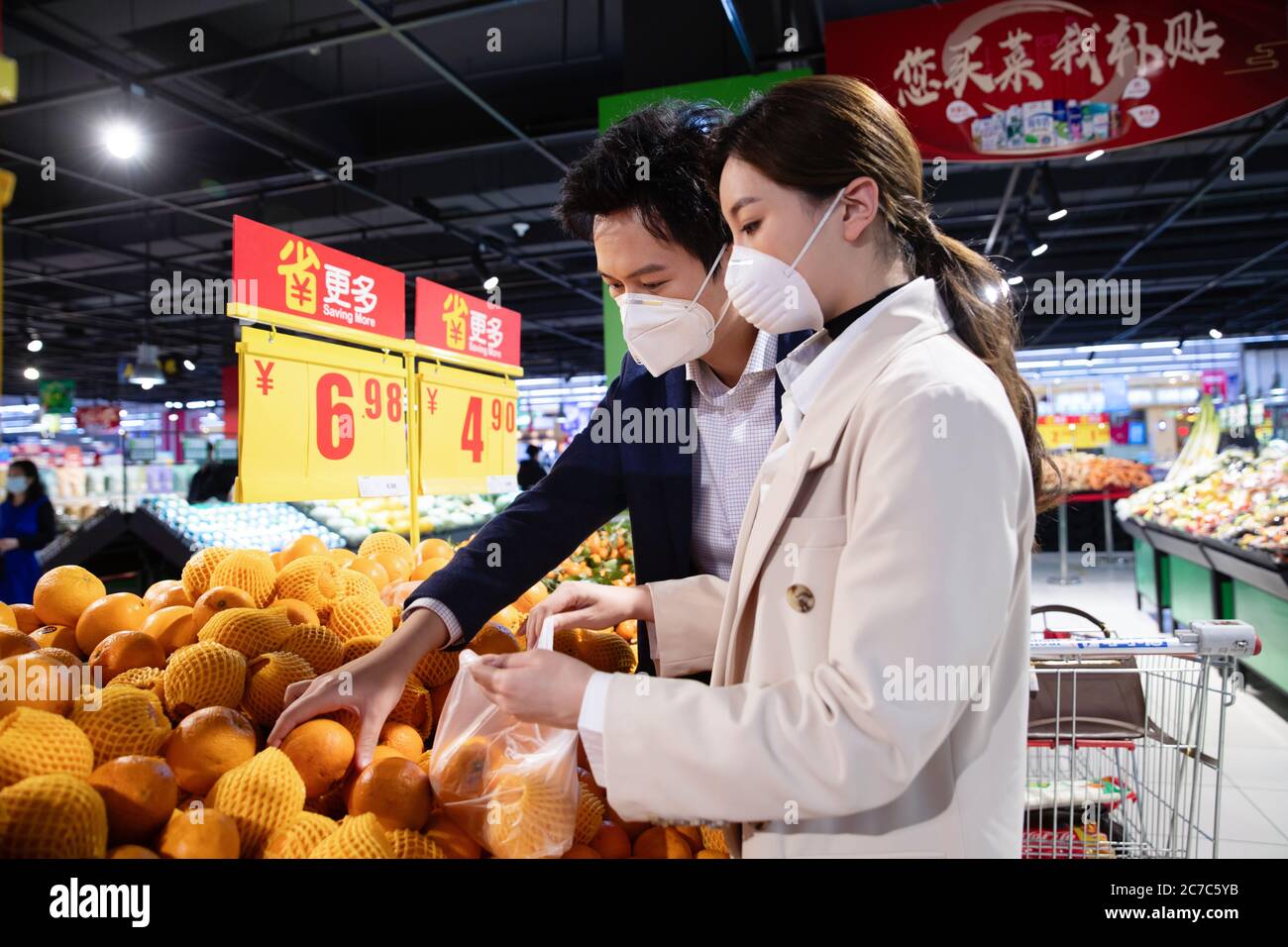 Young couple wearing a mask pick fruit in the supermarket Stock Photo ...