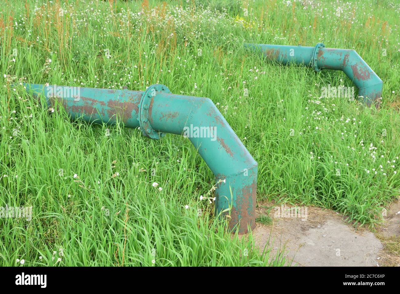 A pipe protruding from the grass on a slope. Summer Stock Photo - Alamy