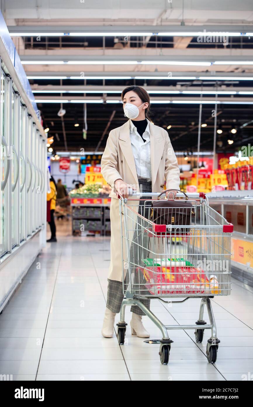 Wearing a mask of young women shopping in the supermarket Stock Photo ...
