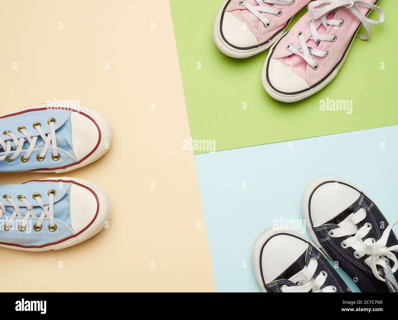 multi-colored well-worn textile sneakers of different sizes on a green ...