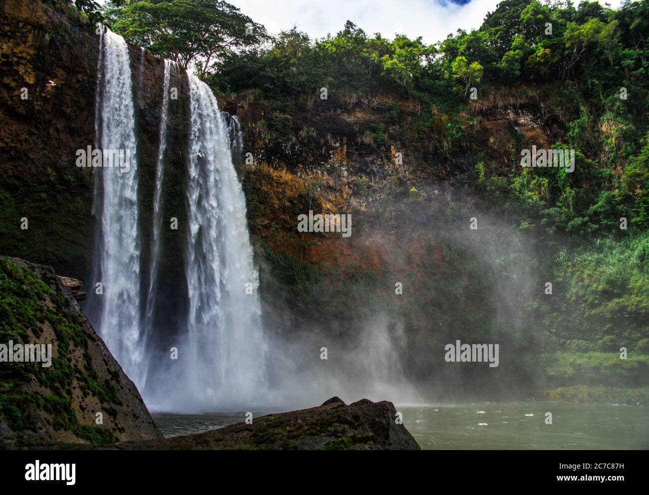 Horizontal shot of a small waterfall flowing from a cliff into a small ...