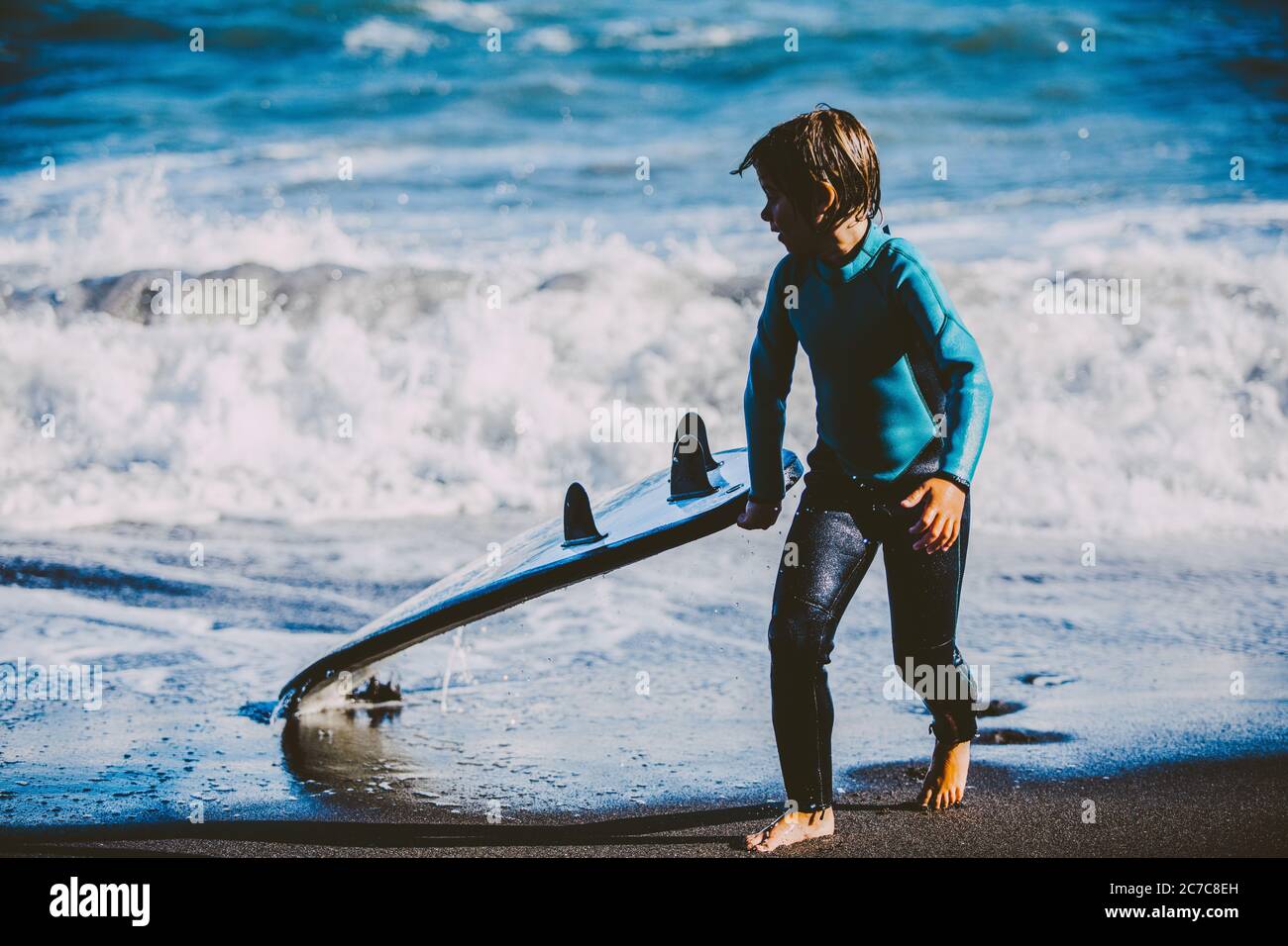 kids enjoying a funny surf day in the shore of a sunny beach in their ...