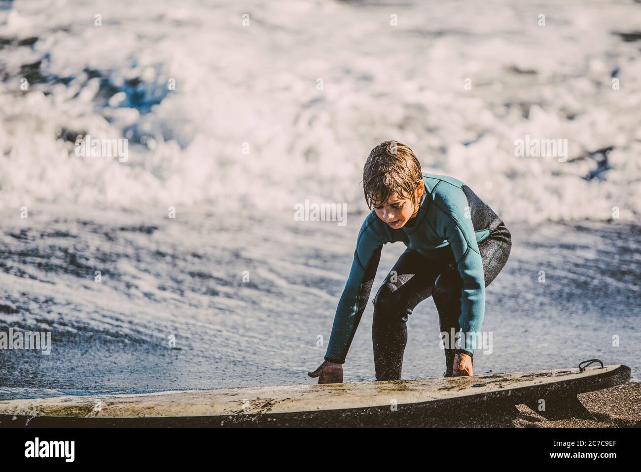 kids enjoying a funny surf day in the shore of a sunny beach in their ...