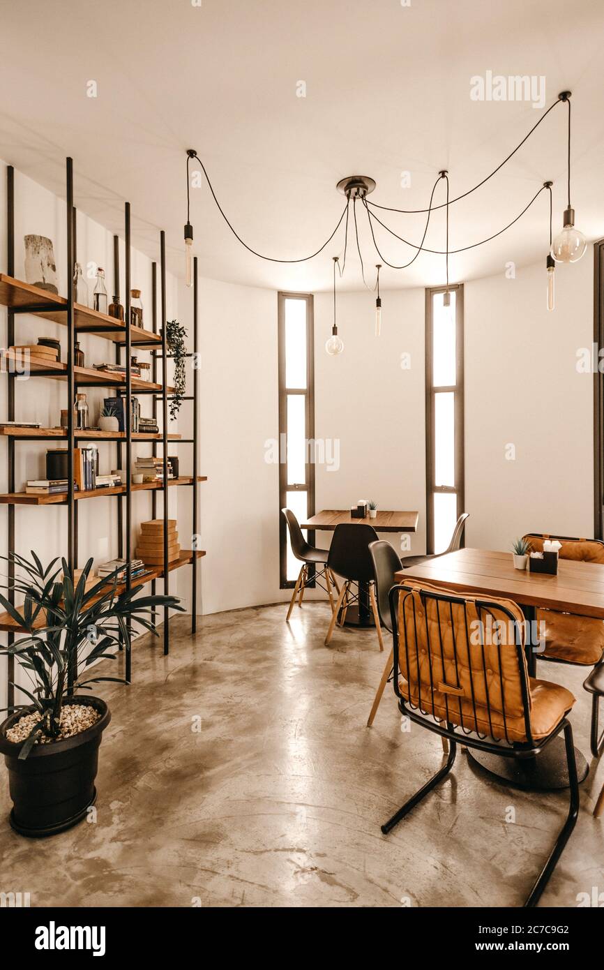 Vertical shot of a cafe interior with tables, chairs, and a bookshelf ...