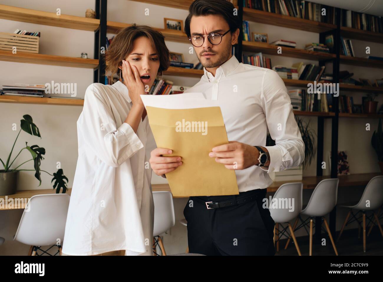 Young disappointed business colleagues standing amazedly reading ...