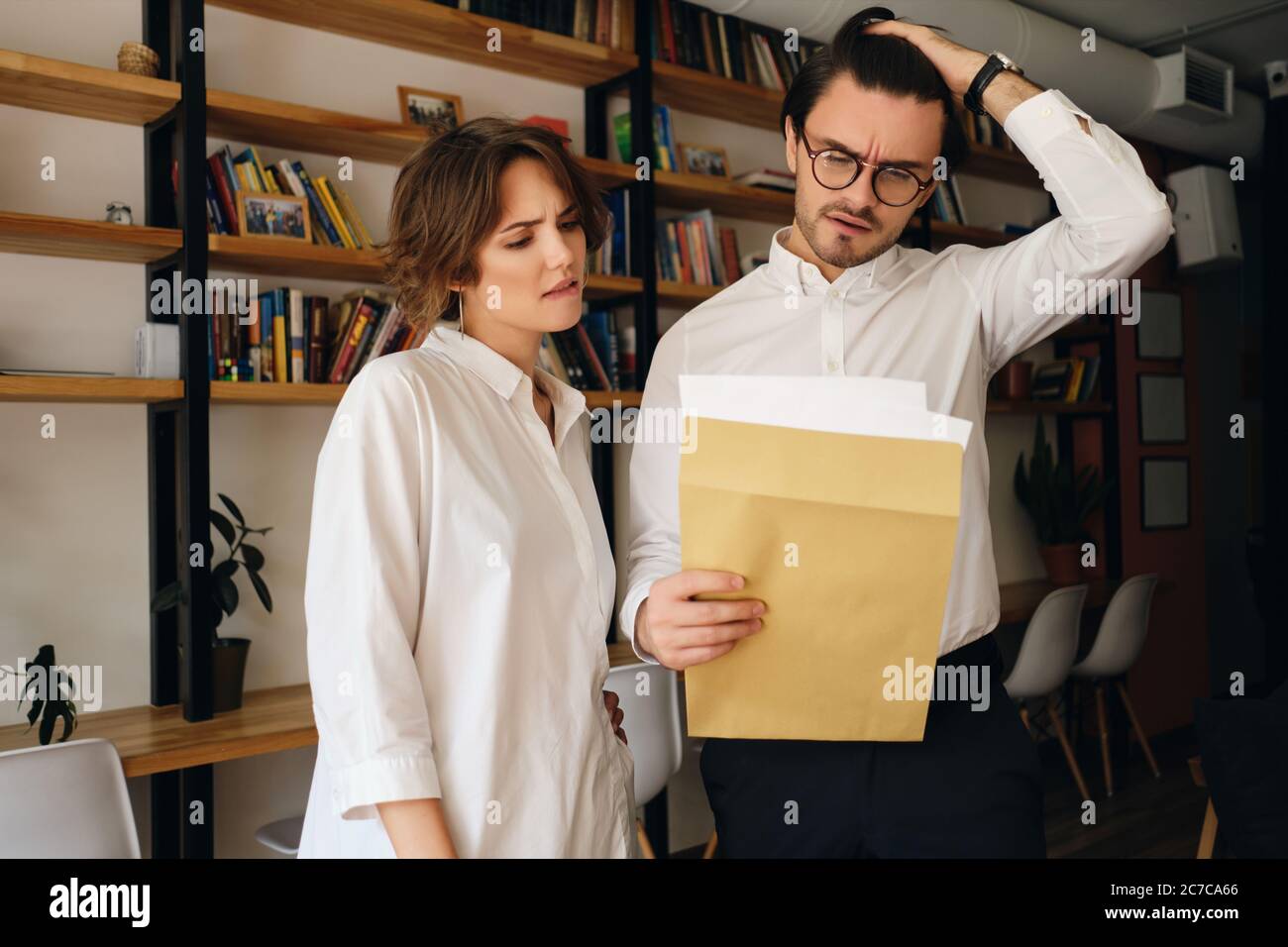 Young disappointed business colleagues thoughtfully reading envelope ...