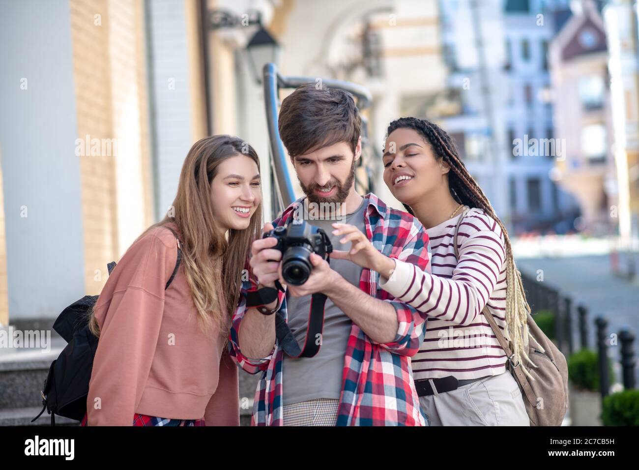 Three young friends looking at the camera screen with interest Stock ...