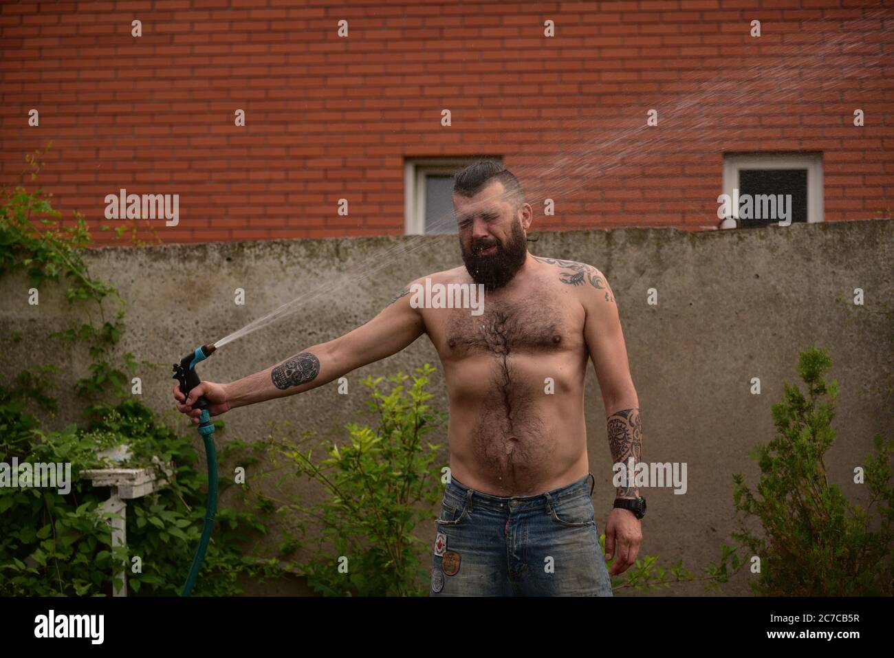 A man douses himself with water from a hose in the street Stock Photo ...