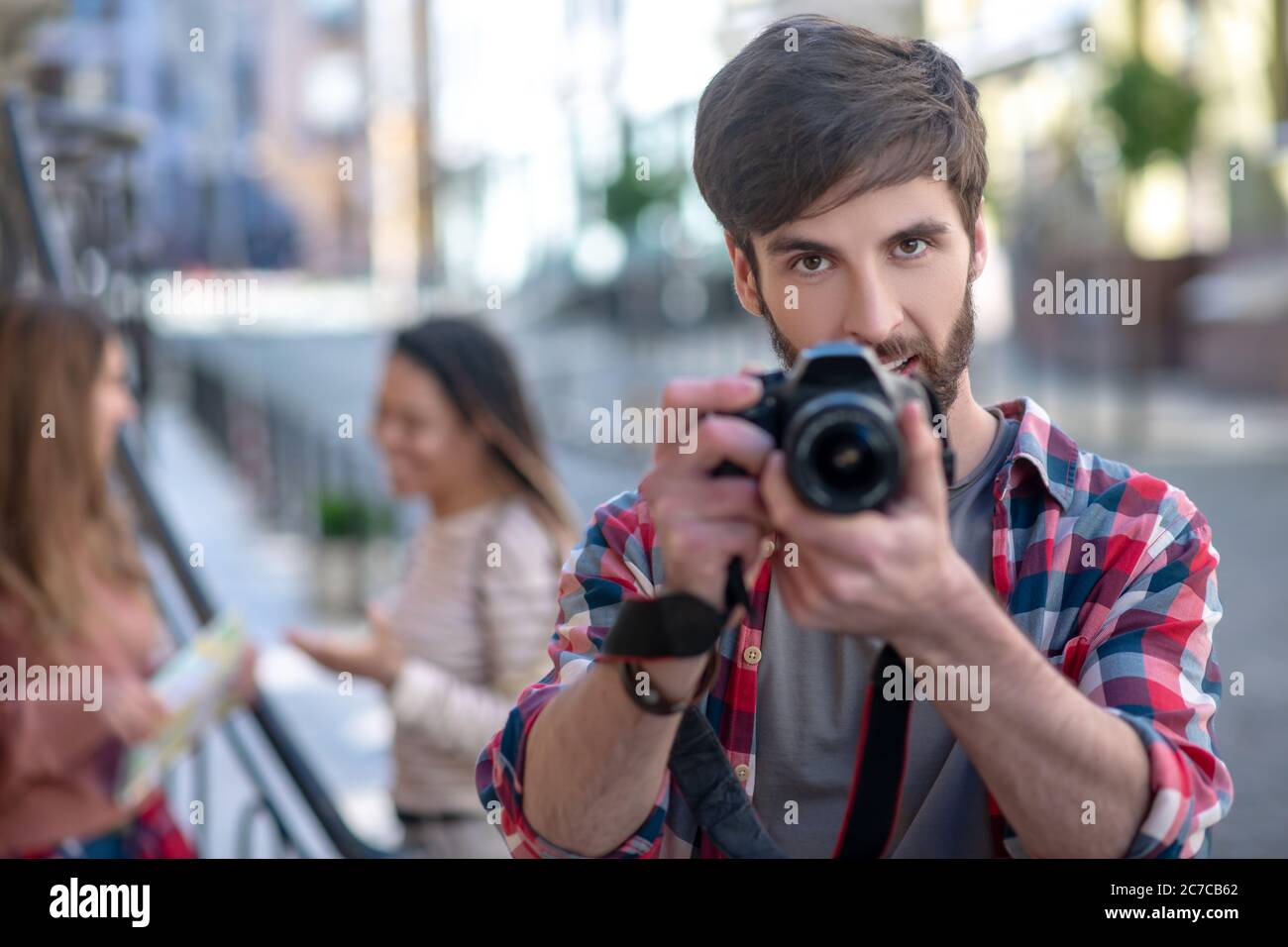 Serious attractive guy with a camera looking straight Stock Photo - Alamy