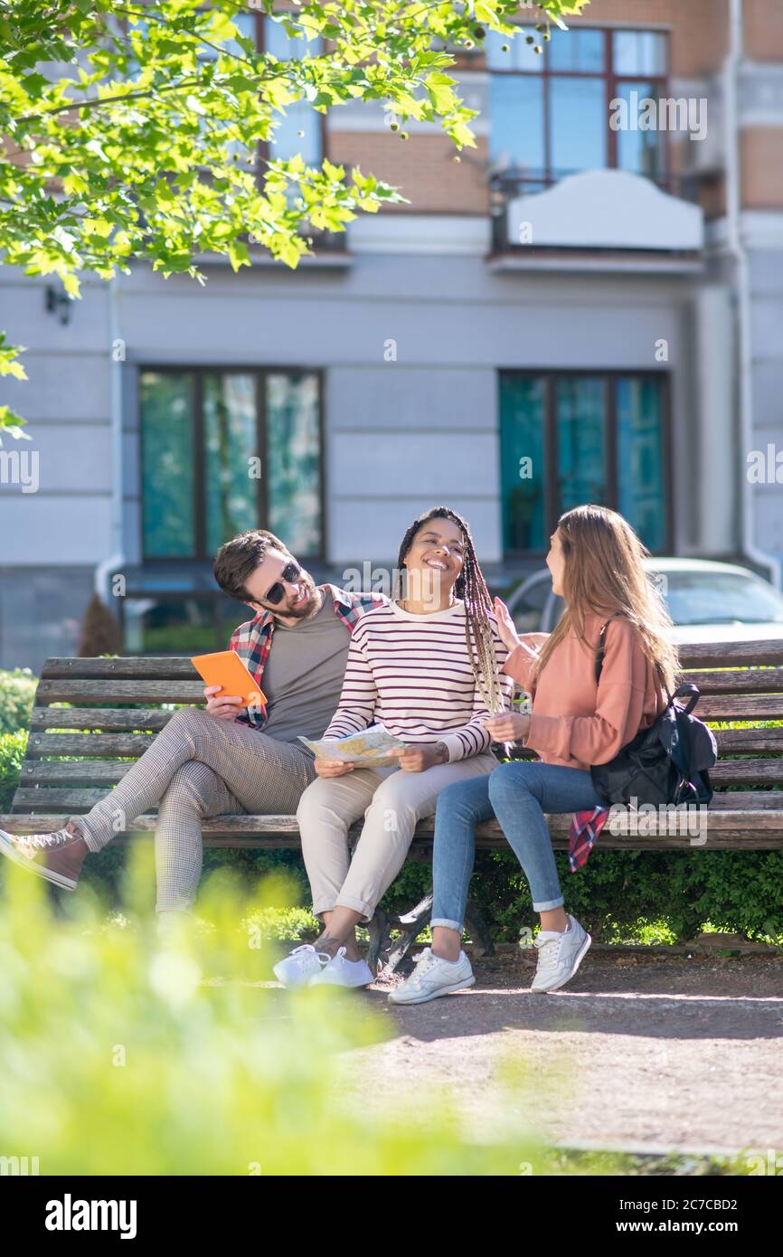 Three friends sitting on a bench near the house Stock Photo - Alamy