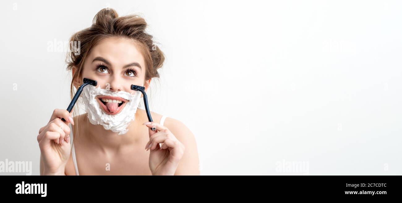 Beautiful young caucasian woman shaving her face by two razors with ...