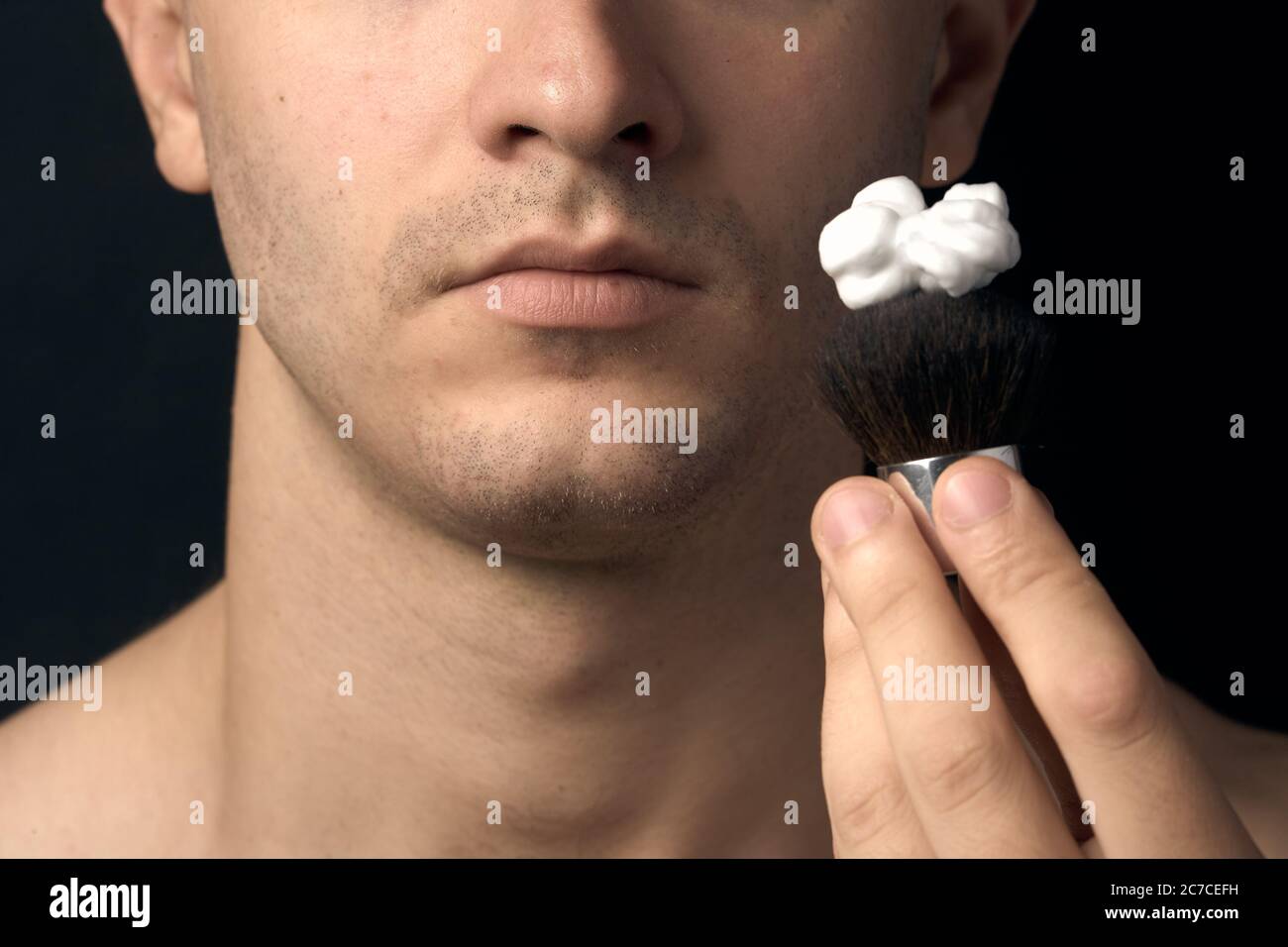 Close-up of a male chin. A man applies shaving foam with a shaving ...