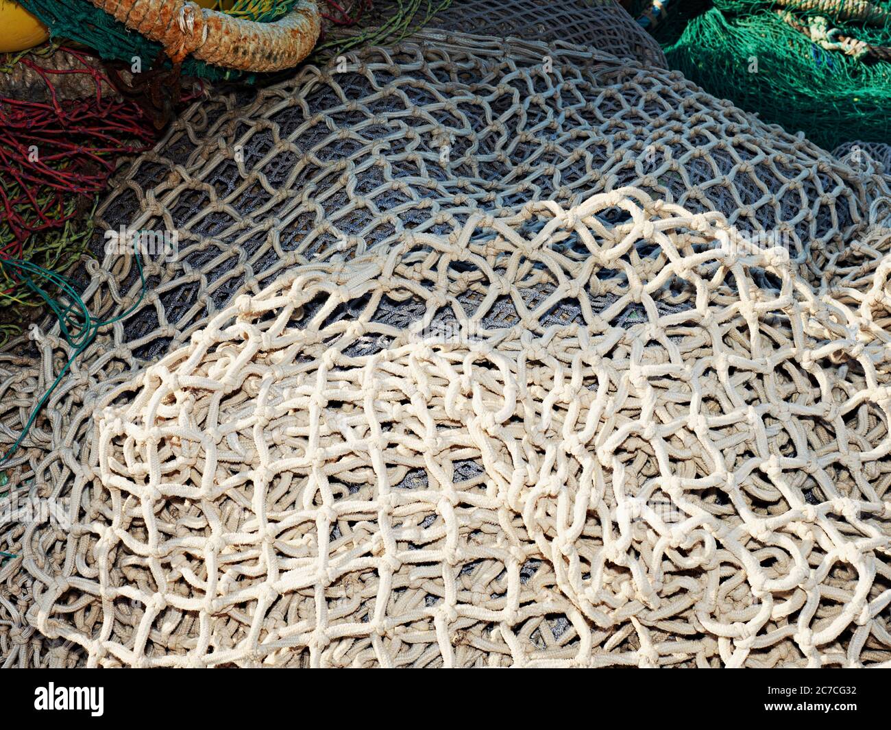 White dry fishing net with floats on pavement at anchored fishing boat ...