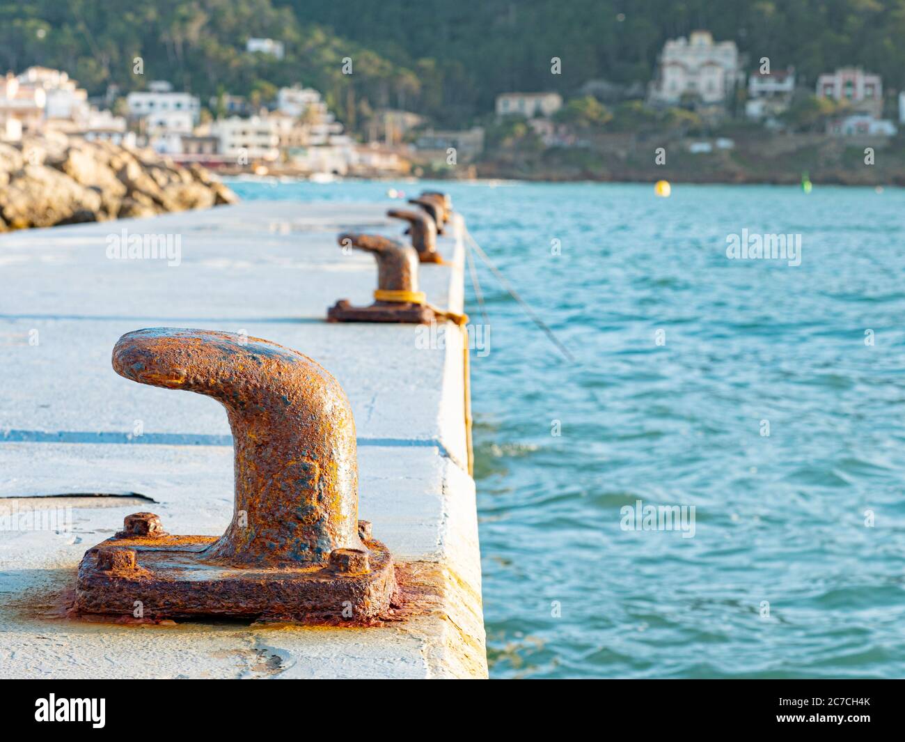 Concrete mole in harbor with bent steel bollards for mooring of ships ...