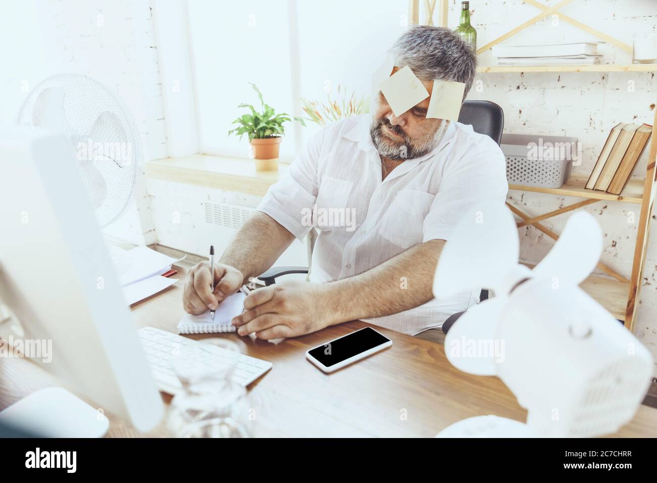 Can't concentrate. Businessman, manager in office with computer and fan ...