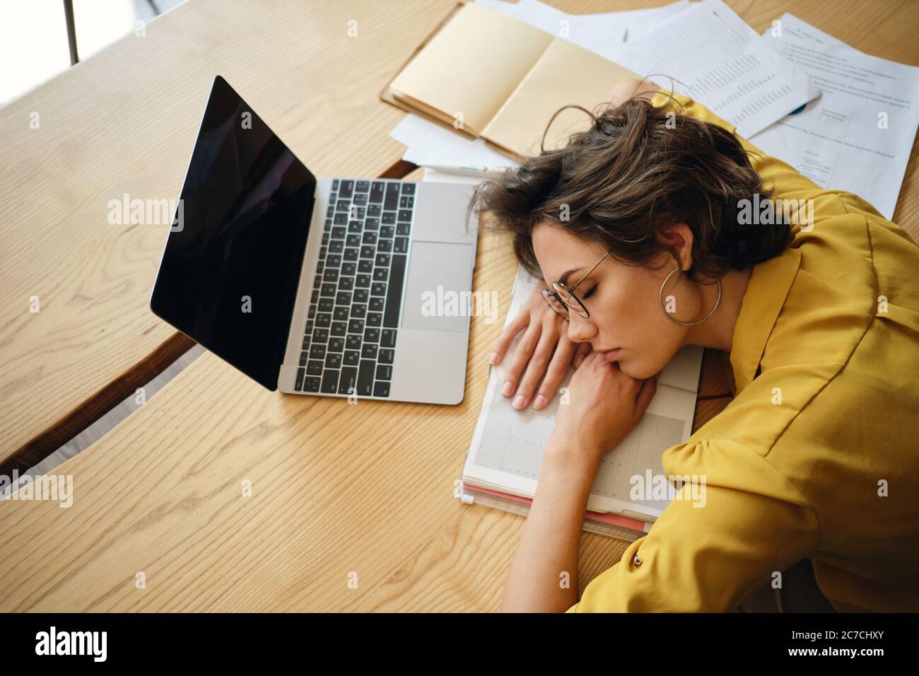 Top view of young tired woman dreamy asleep on desk with laptop and ...
