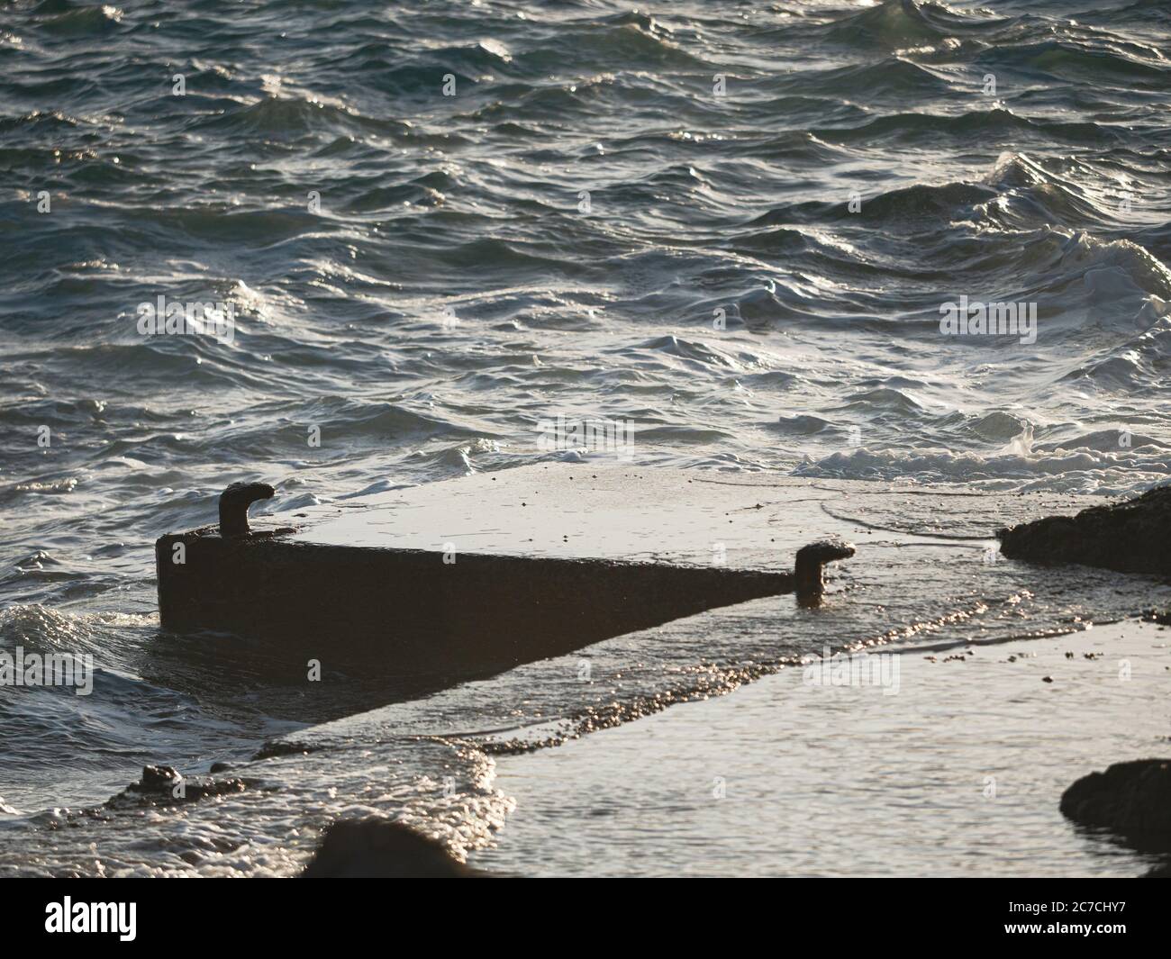 Concrete mole in harbor with bent steel bollards for mooring of ships ...
