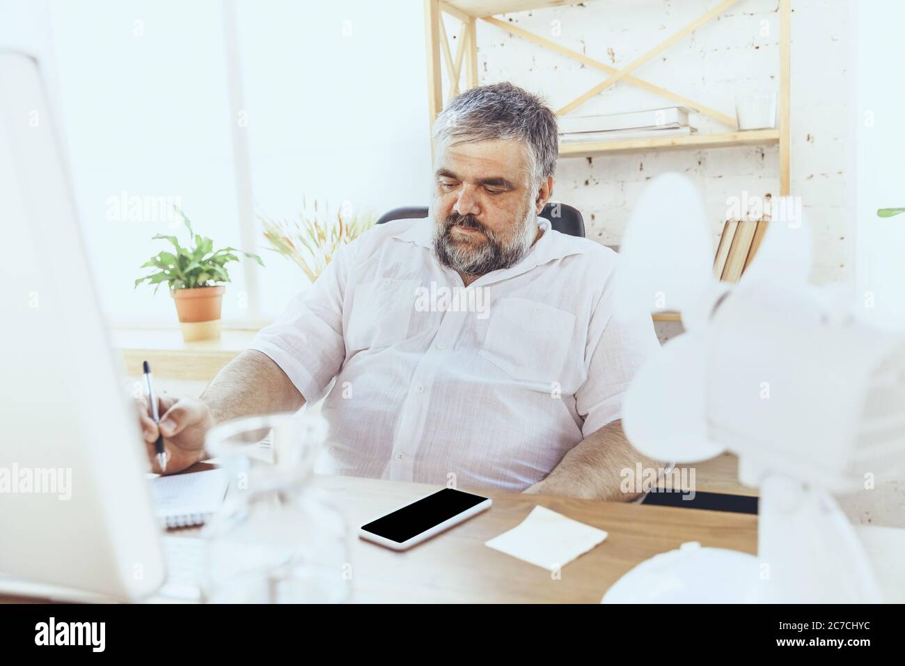 Can't concentrate. Businessman, manager in office with computer and fan ...