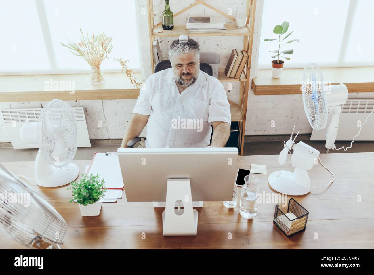 Ice helping. Businessman, manager in office with computer and fan ...