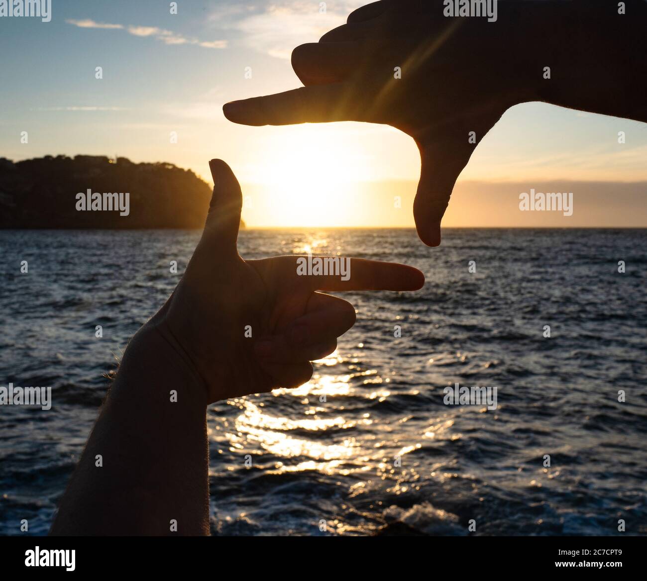 Hands catch sun at sunset time. Female fingers hold sun above lake ...