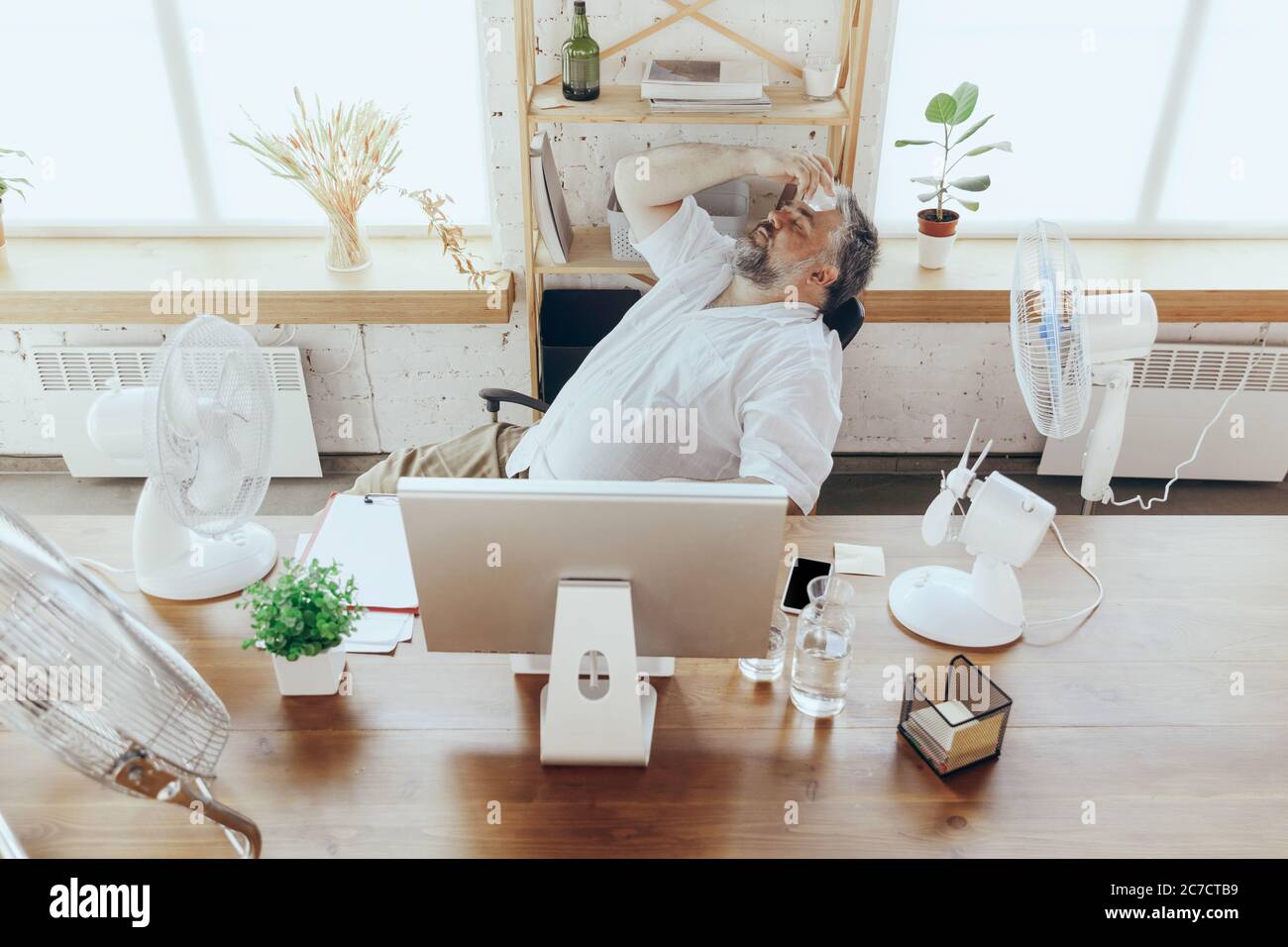 Ice helping. Businessman, manager in office with computer and fan ...