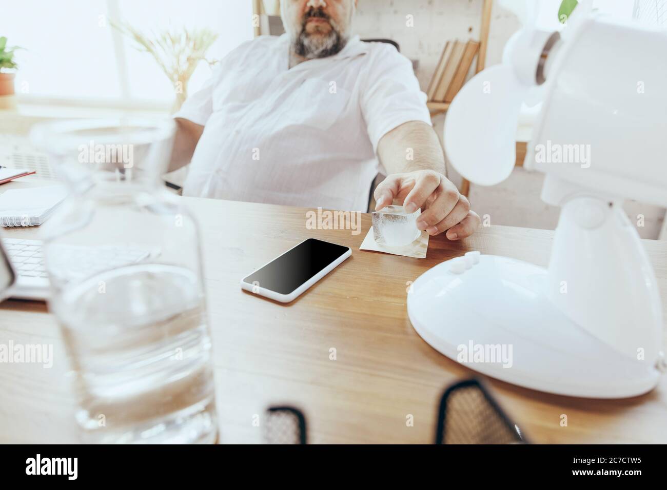 Ice helping. Businessman, manager in office with computer and fan ...