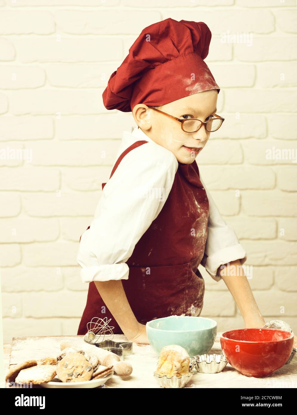 young boy cute cook chef in red uniform and hat on stained face with ...