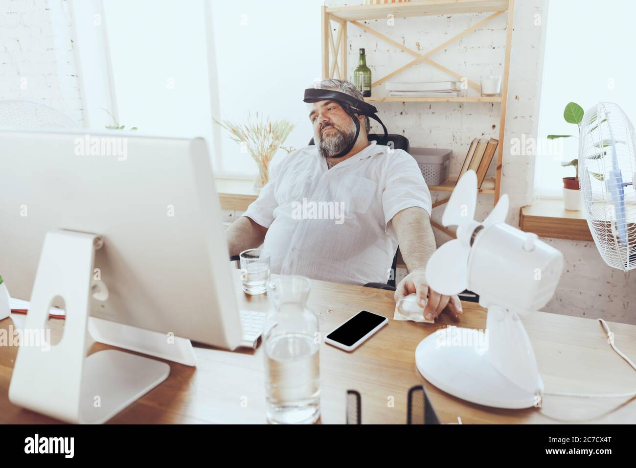 Wind. Businessman, manager in office with computer and fan cooling off ...