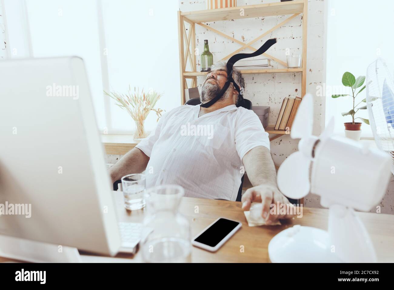 Wind. Businessman, manager in office with computer and fan cooling off ...