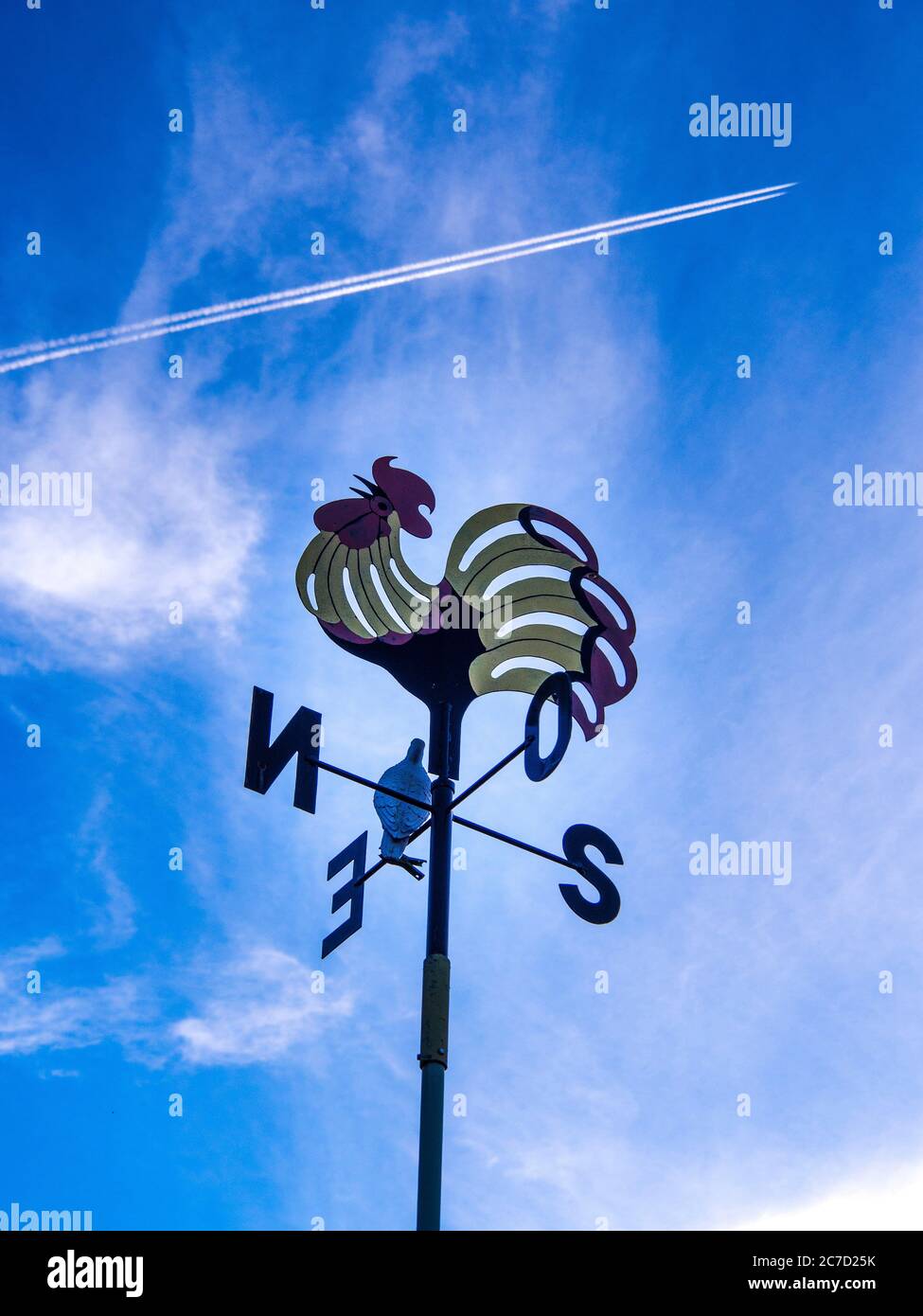 Wind vane with rooster design points to the cardinal directions under a ...