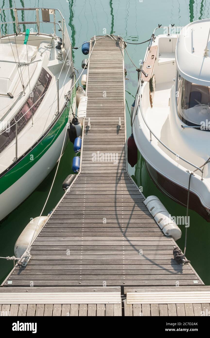 small boats moored to a jetty in a calm water ocean marina Stock Photo ...