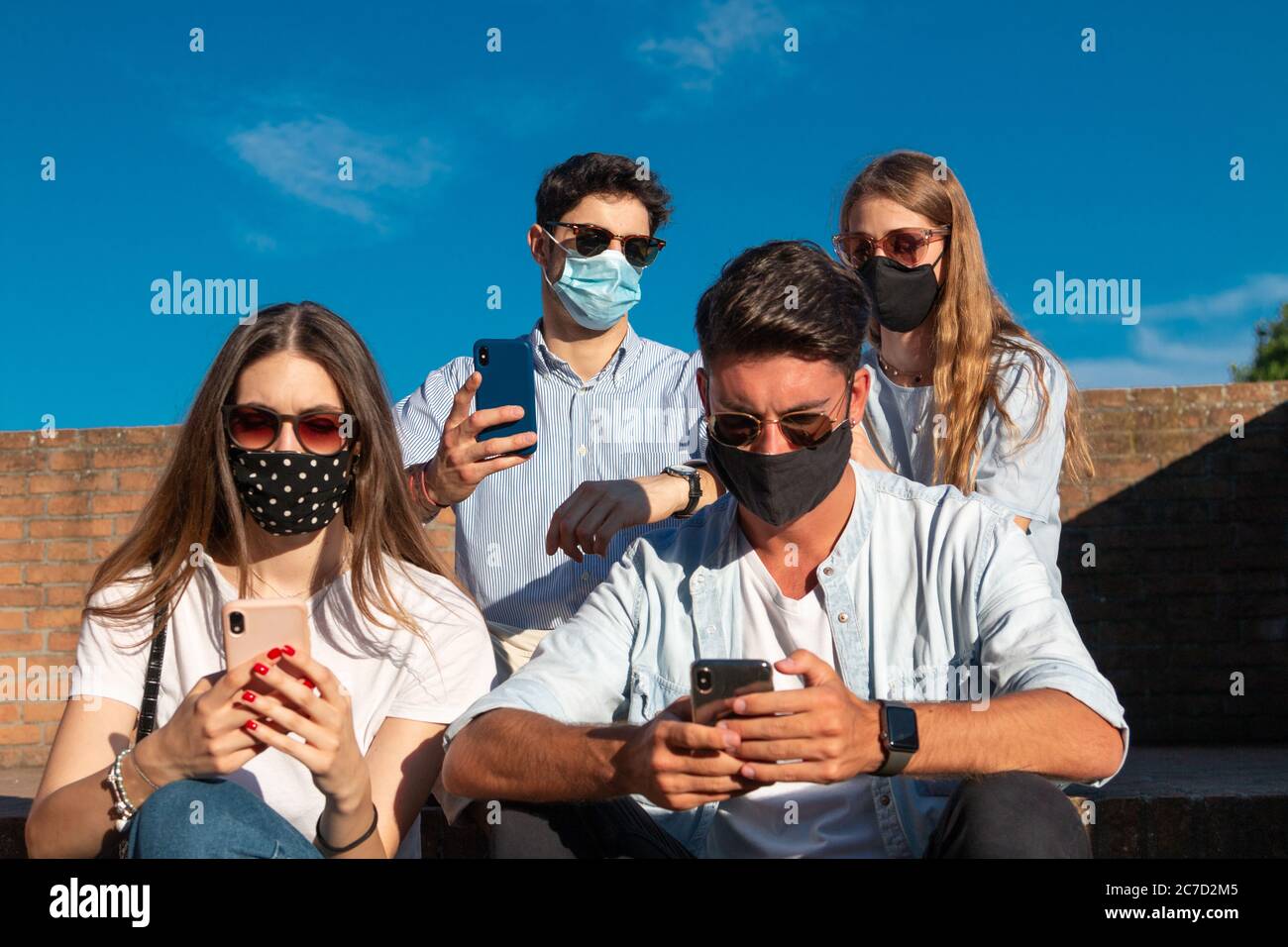 group of friends using smartphone wearing face mask - friendship during ...