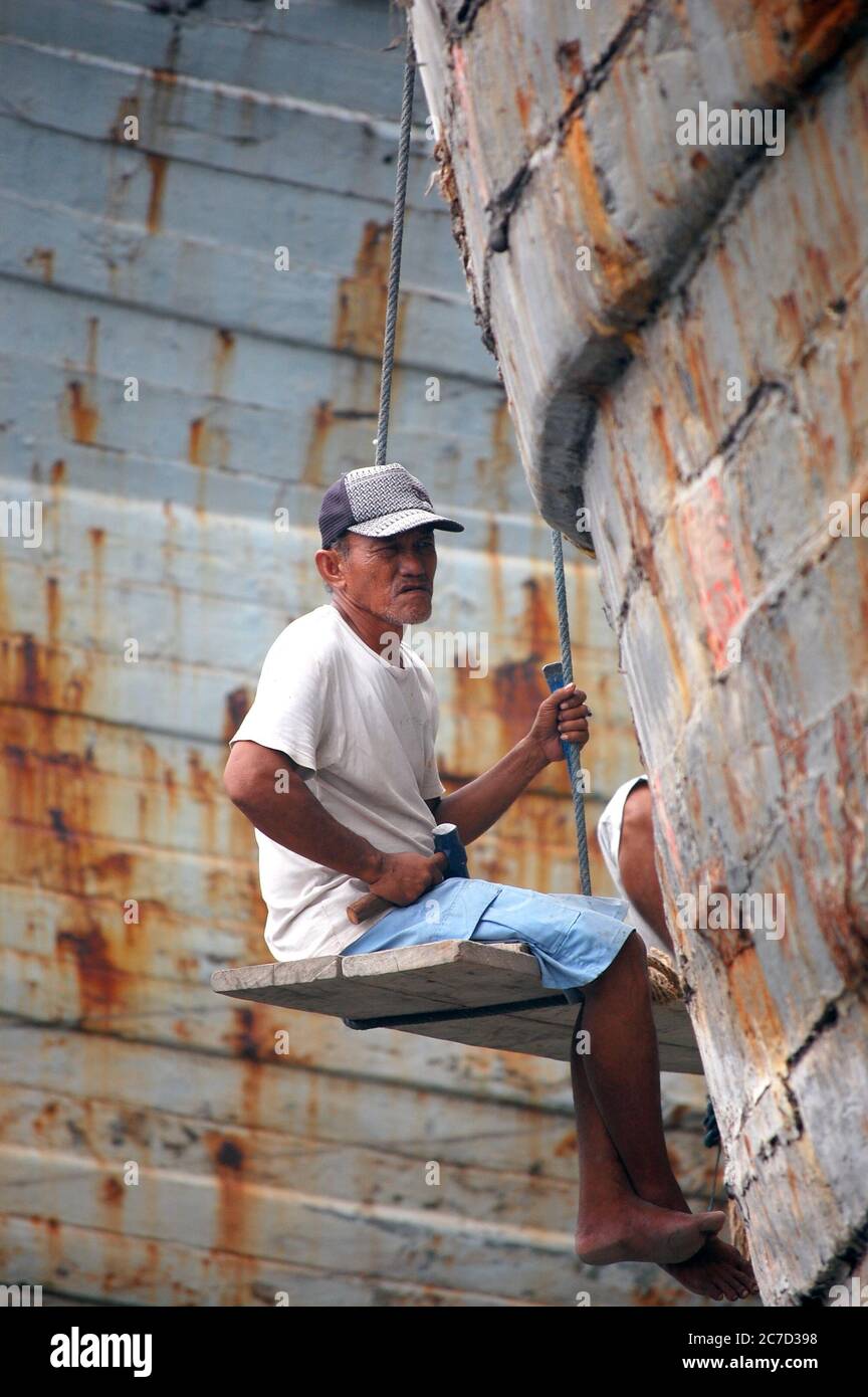 JAKARTA, INDONESIA - Mar 07, 2014: man repairing a boat in dock area ...