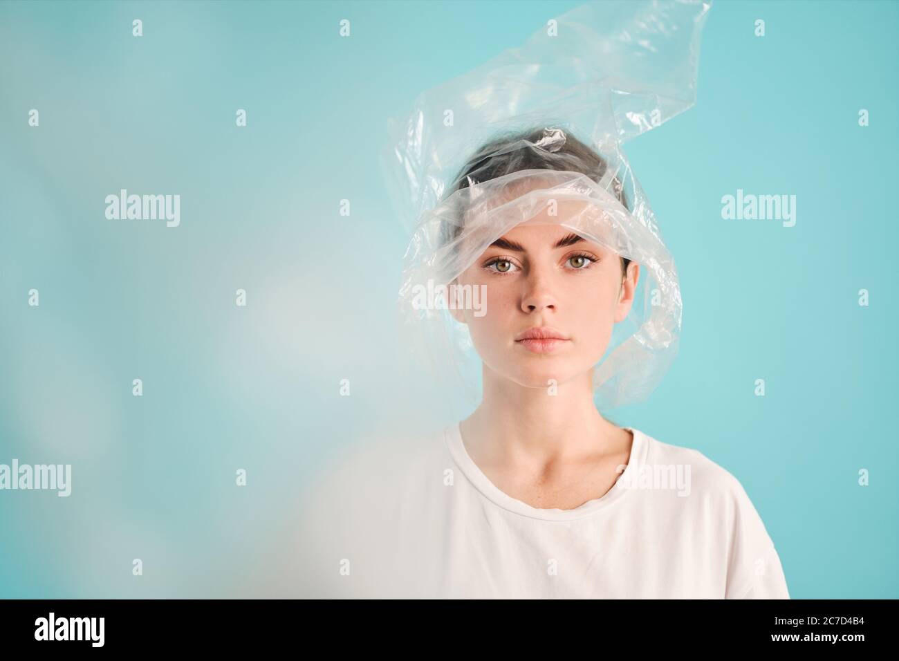 Serious girl with plastic bag on head confidently looking in camera ...