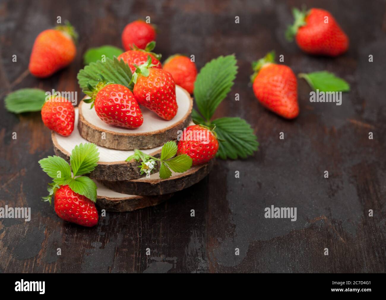 Organic fresh raw strawberries with leaf on timber round boards on dark ...