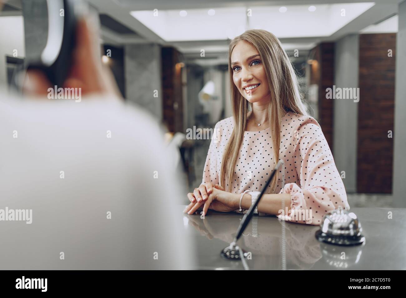 Blonde woman hotel guest checking-in at front desk in hotel Stock Photo ...