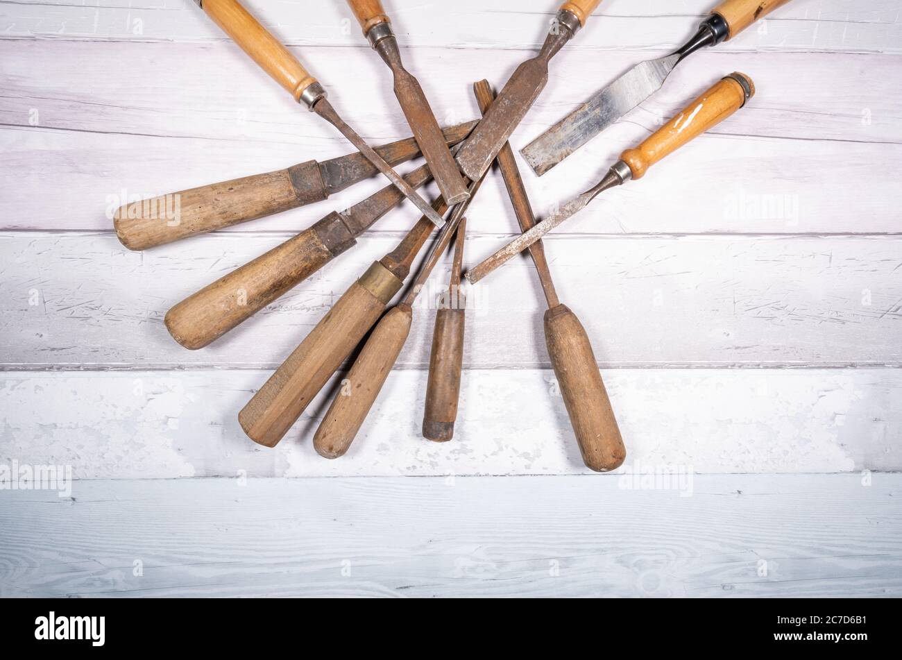 Assortment of old wood chisels on a background of old boards. Top view ...