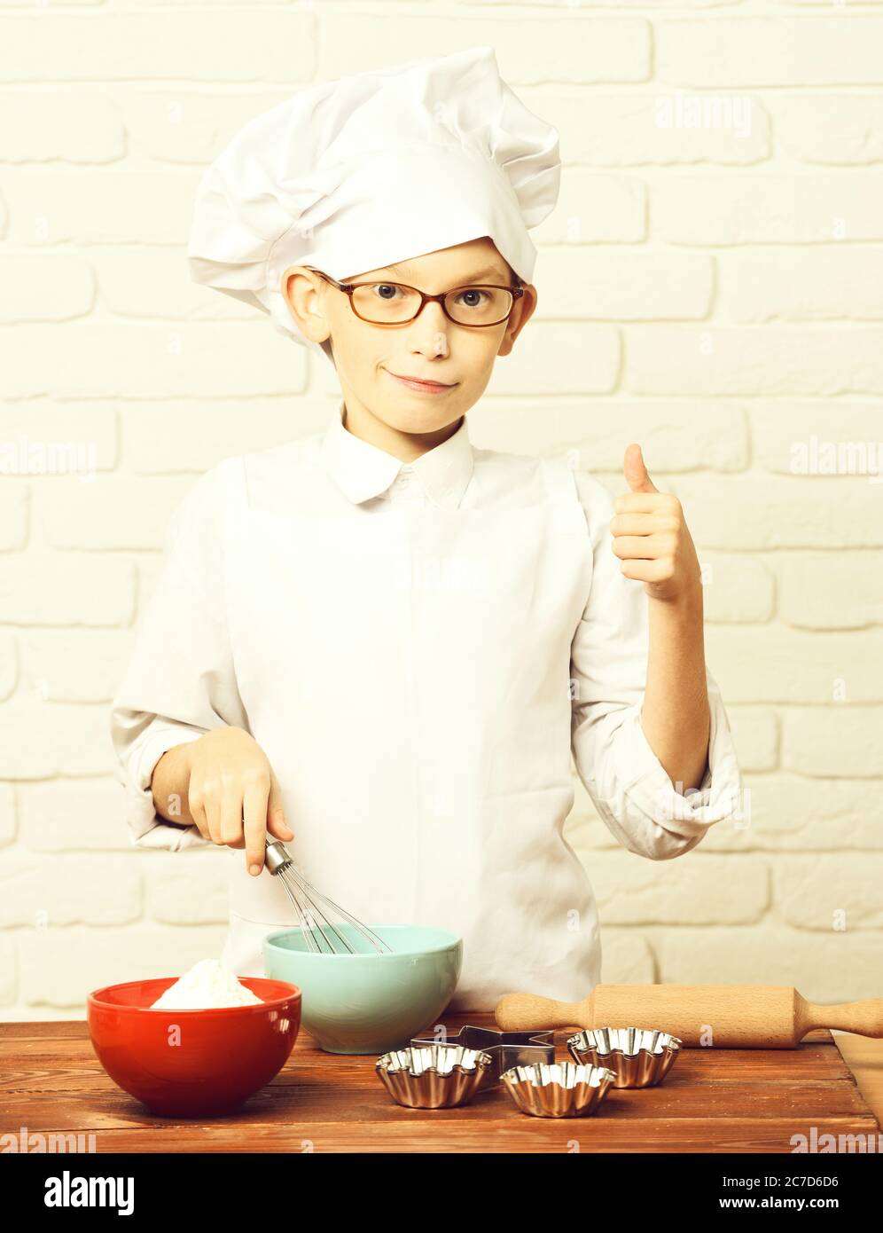 young small cute cook chef in white uniform and hat on smiling face ...