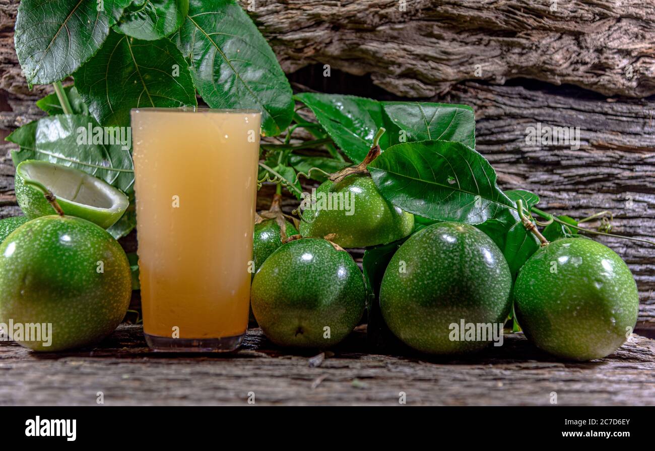 fresh and frozen passion fruit juice. Green fruits. Leaves on wooden ...