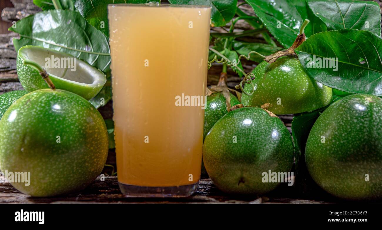fresh and frozen passion fruit juice. Green fruits. Leaves on wooden ...