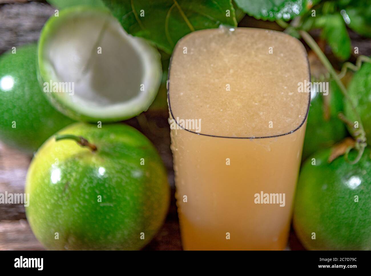 fresh and frozen passion fruit juice. Green fruits. Leaves on wooden ...