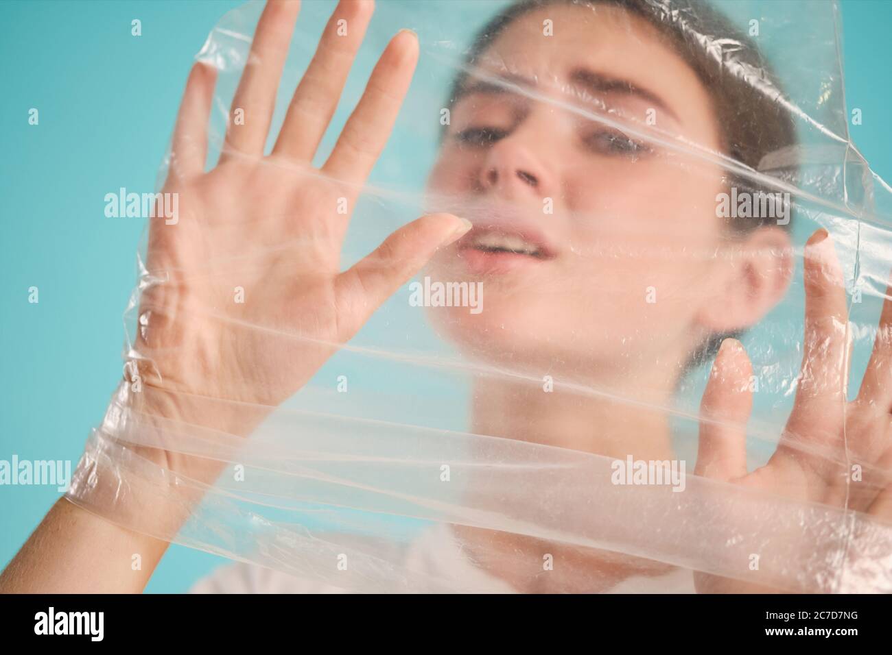 Depressed girl choking in plastic bag unhappily looking in camera over ...