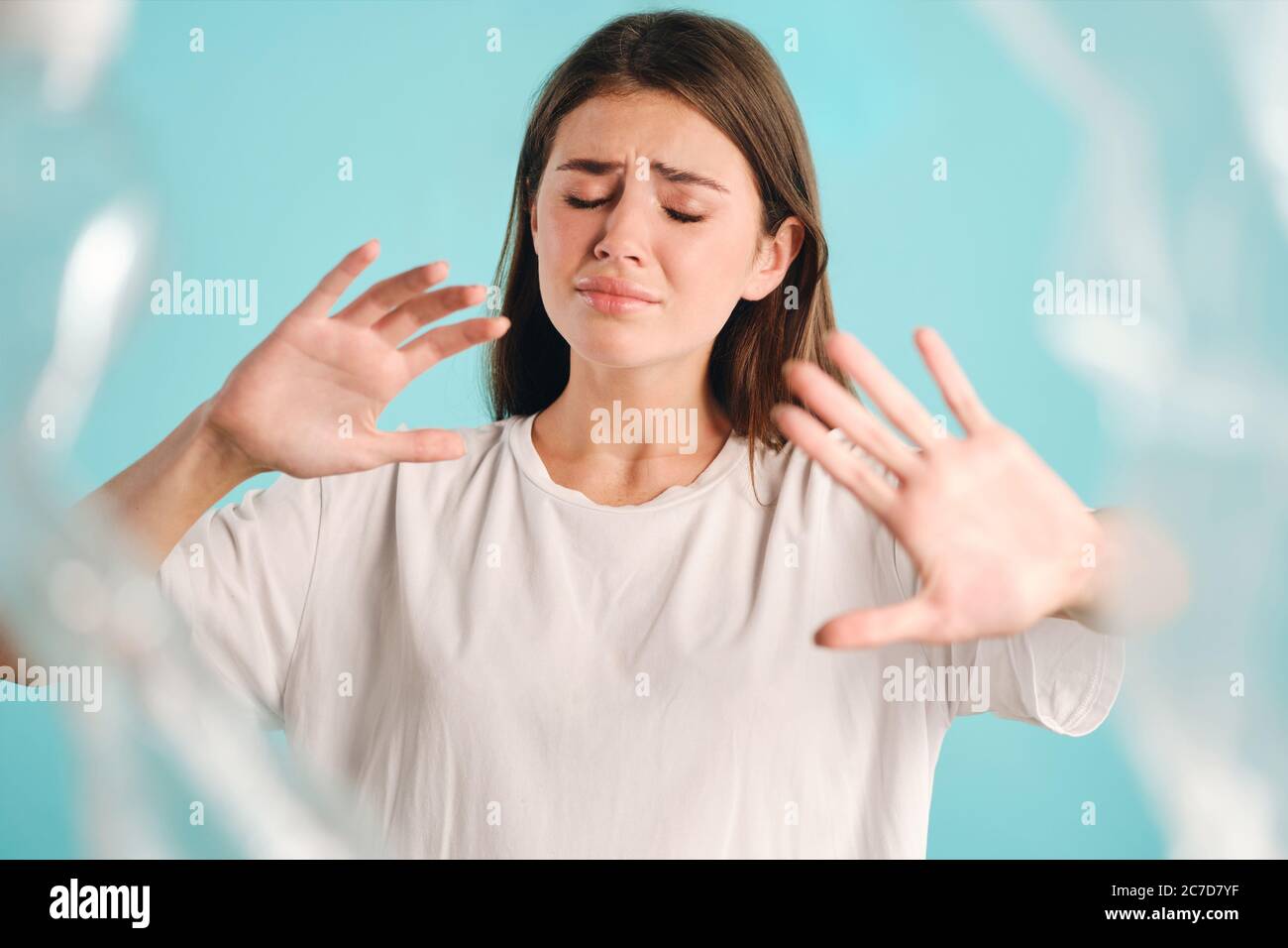 Upset casual girl sadly showing stop gesture to plastic over colorful ...